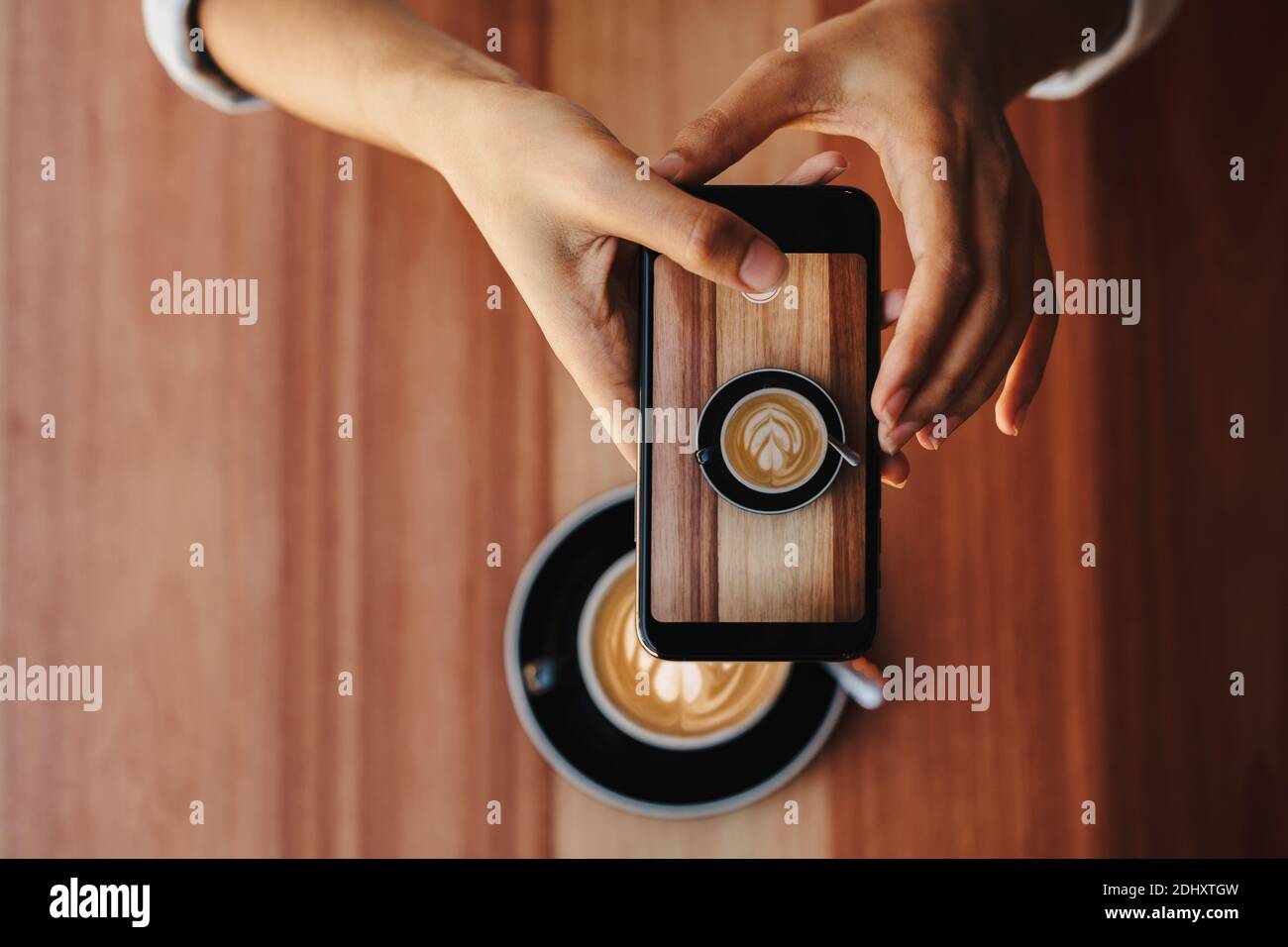 Hand of a woman taking photograph of a coffee with her mobile phone ...