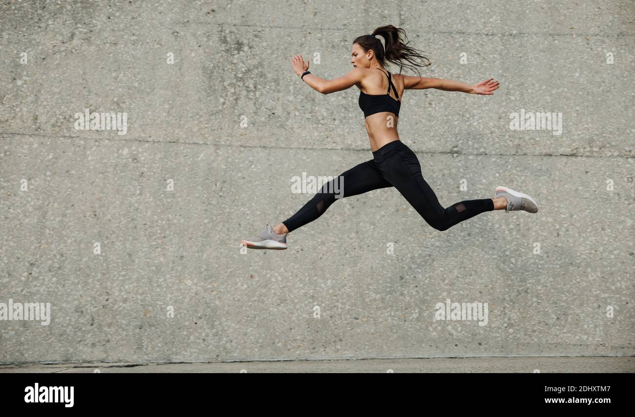 Female athlete running and jumping. Side view of flexible female ...