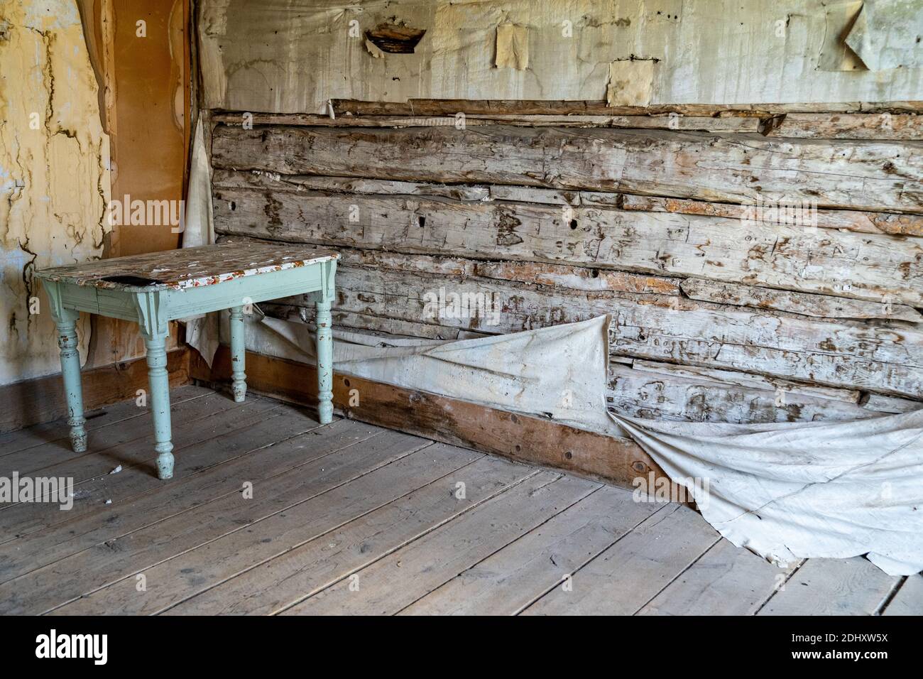 Old, rotting walls in an abandoned building with a table pushed in the ...