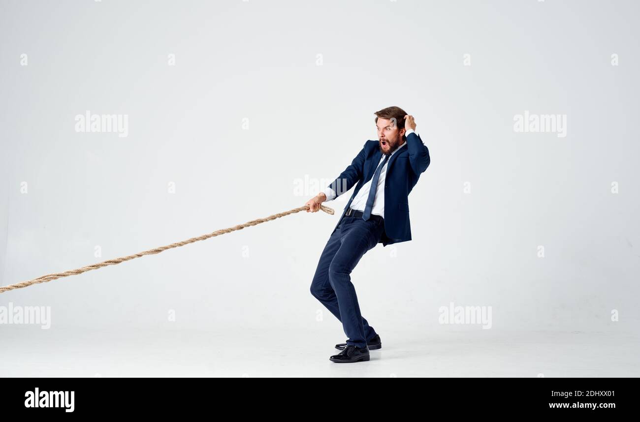 business man with a rope in his hands on a light background tension ...