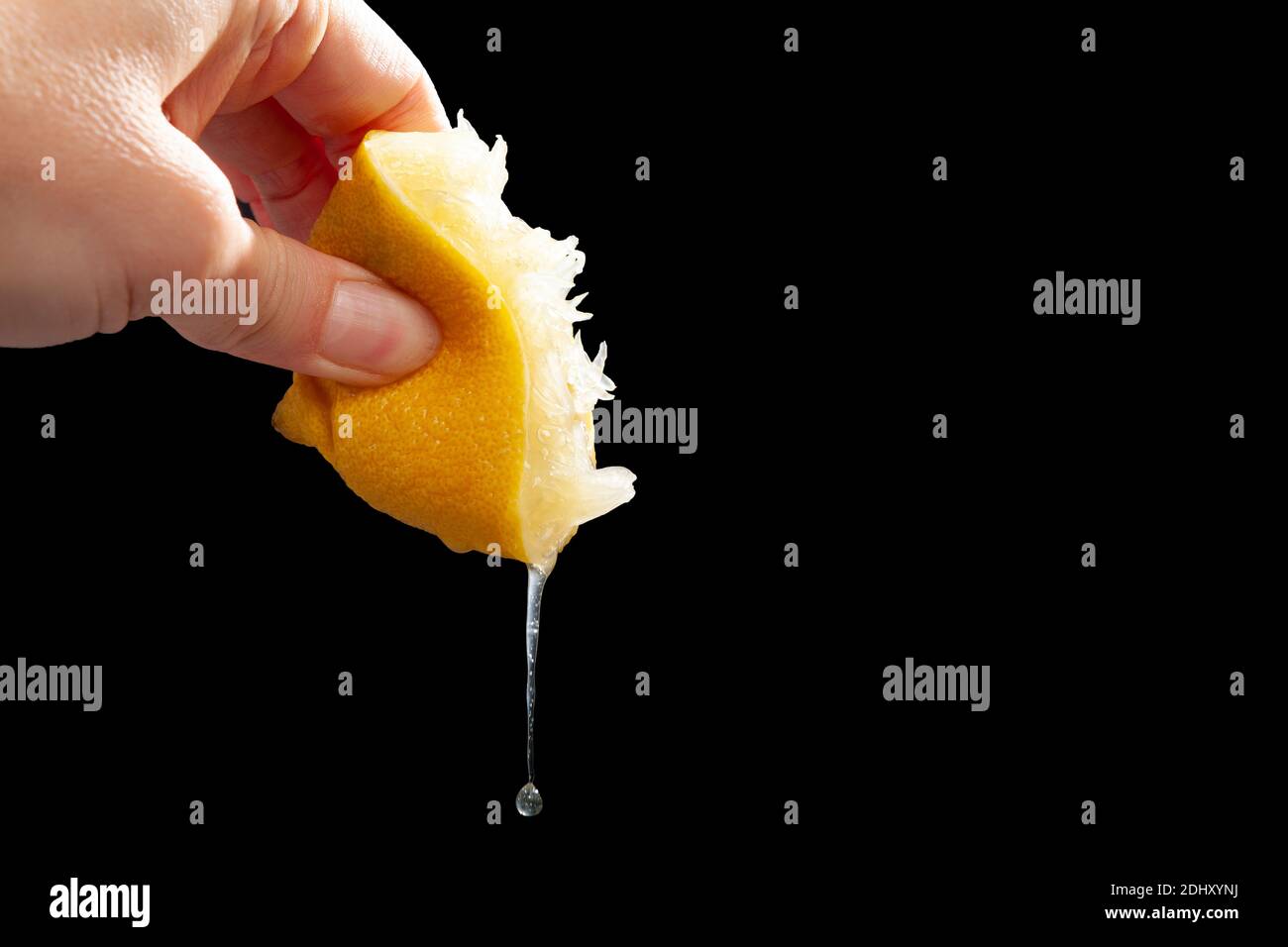 Female hand squeezing half of lemon on black background Stock Photo - Alamy