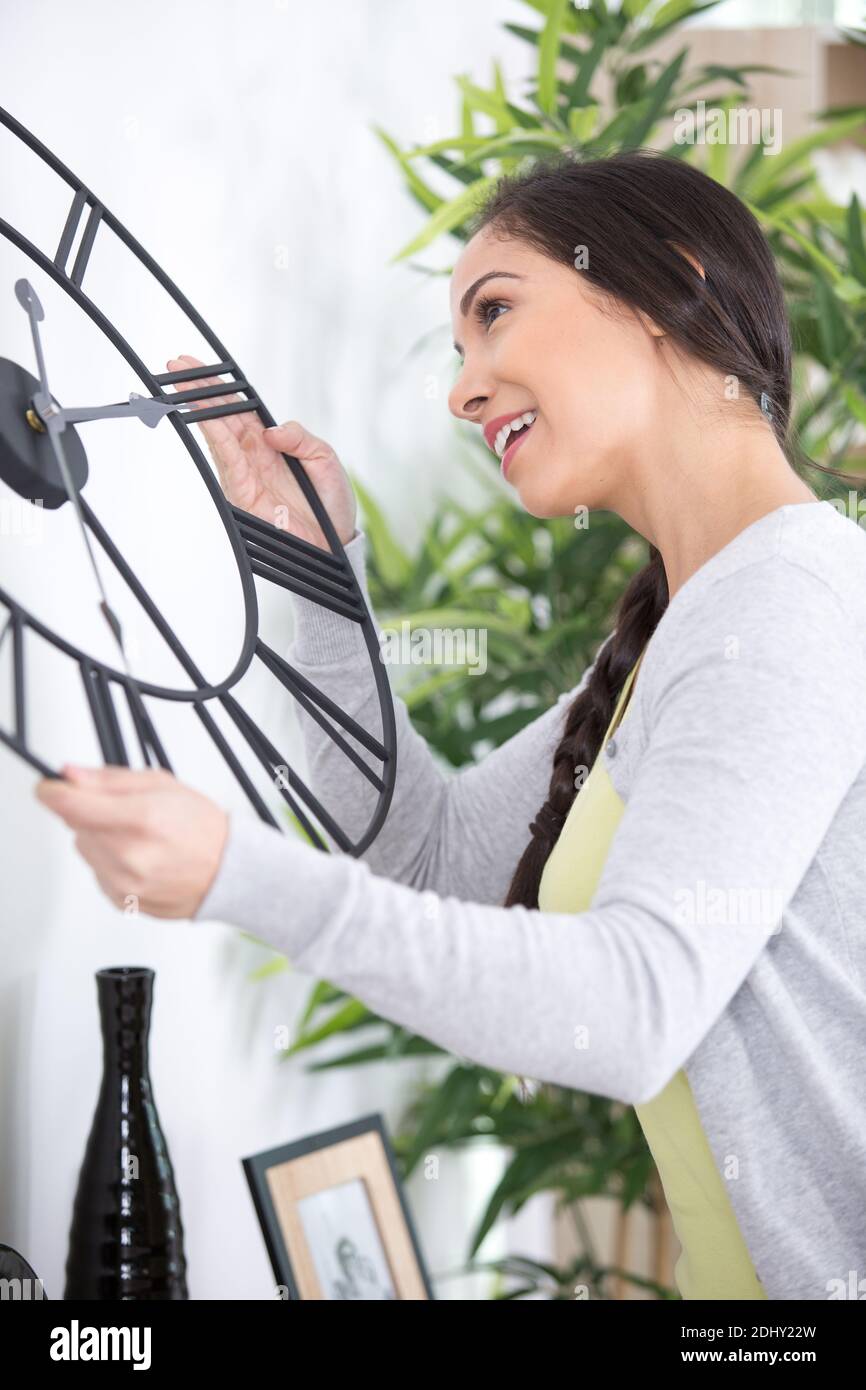happily smiling woman putting clock on the wall Stock Photo - Alamy