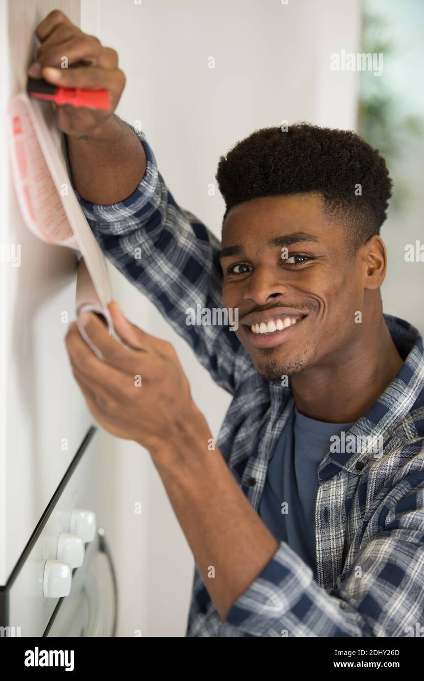 Young handyman couple wallpapering the wall with woodchip wallpaper ...