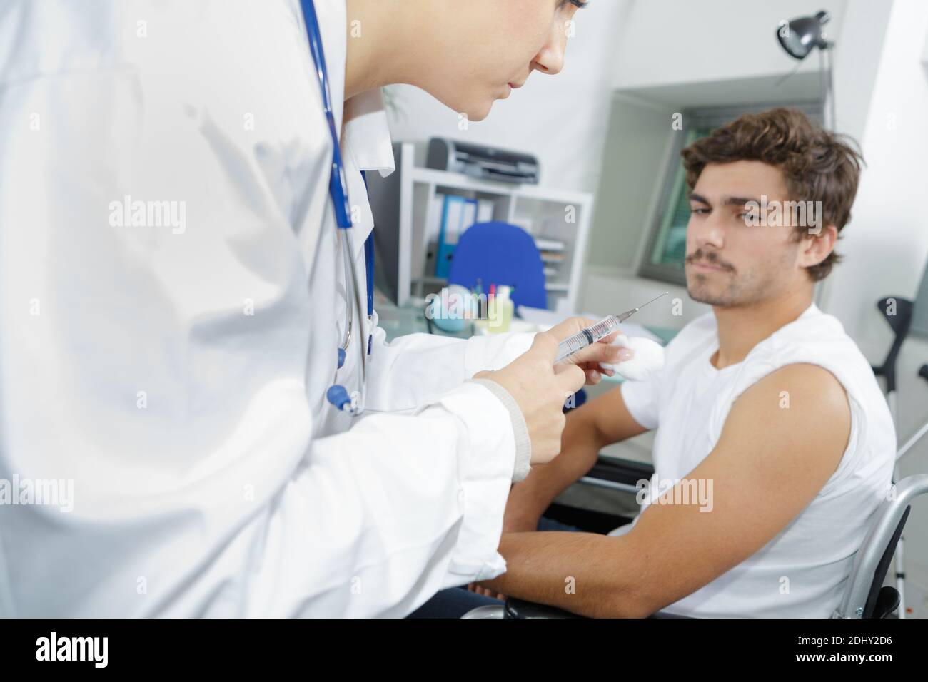 young man receiving injection from medical assistant in clinic Stock ...