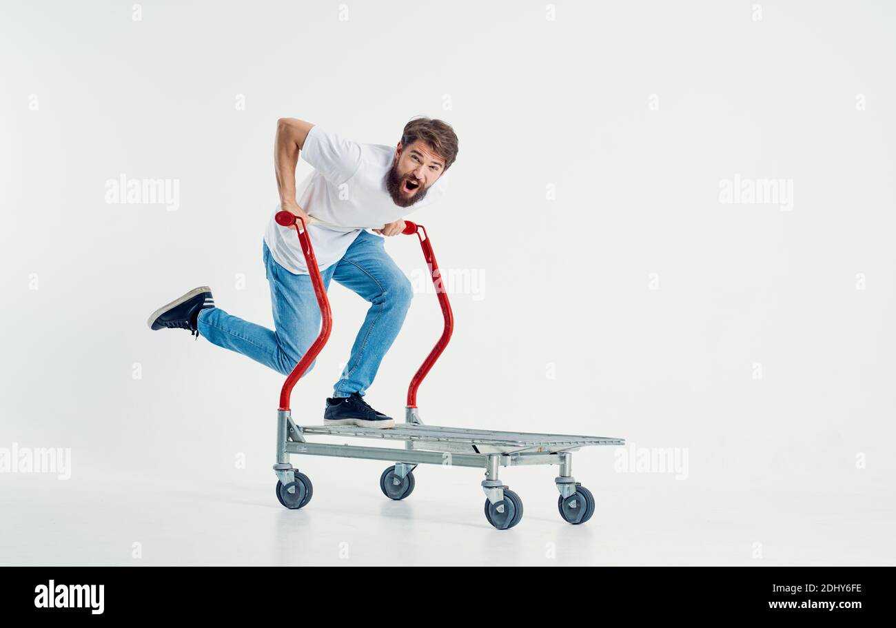 man with a trolley in his hand on a light background transporting heavy ...