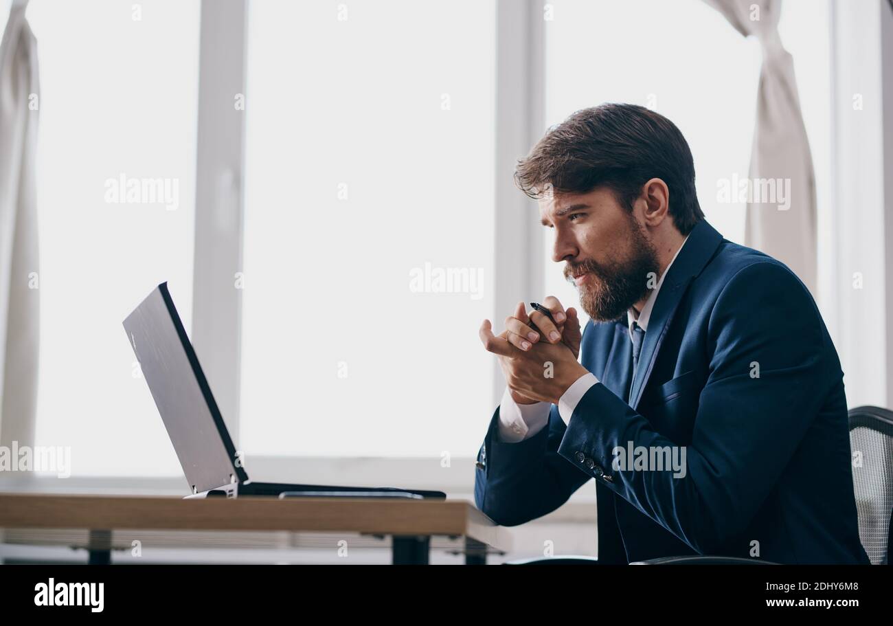Puzzled business man looks at the laptop at the table in the office ...