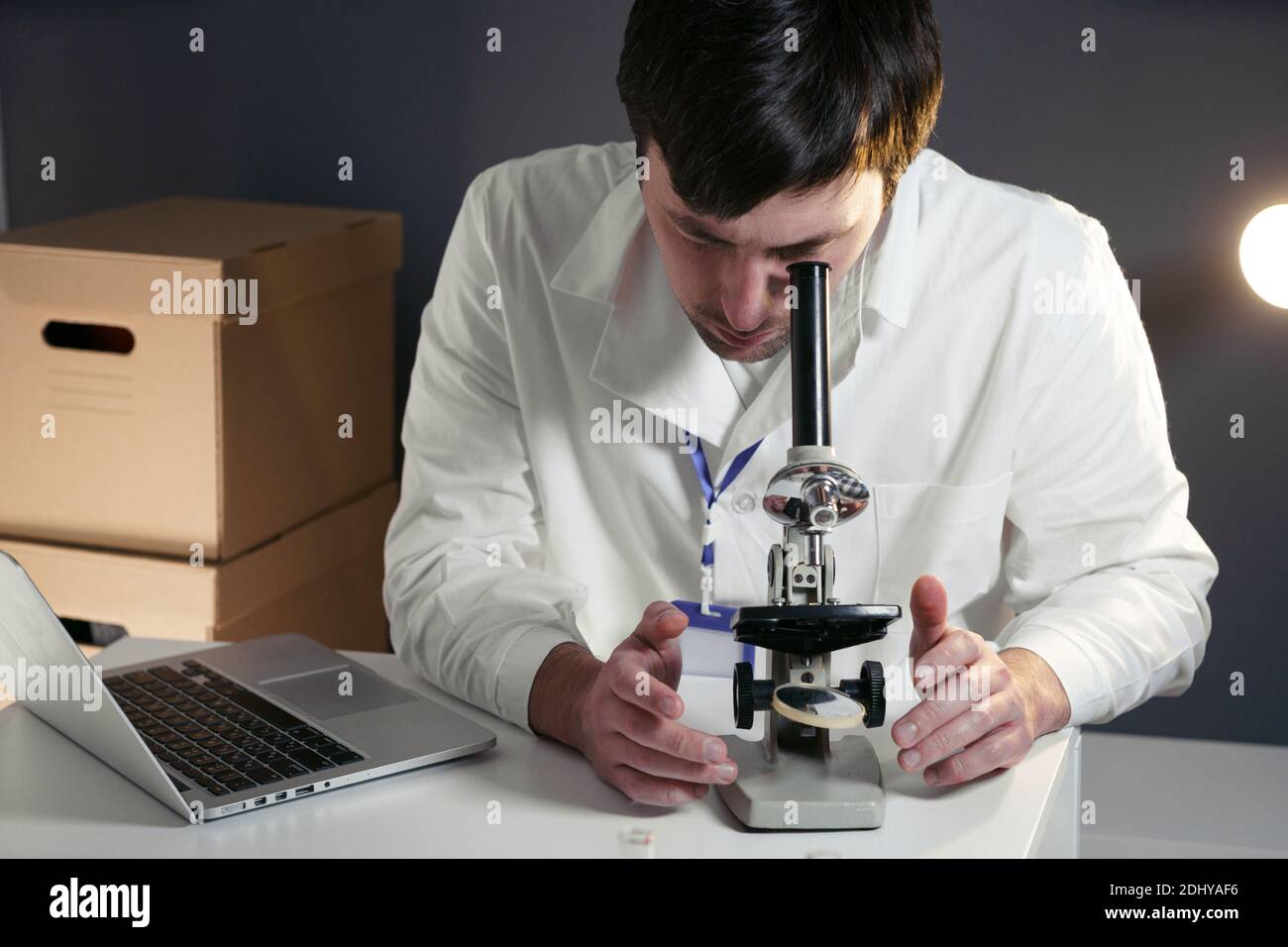 Scientist at workspace in laboratory with microscope, computer, and ...