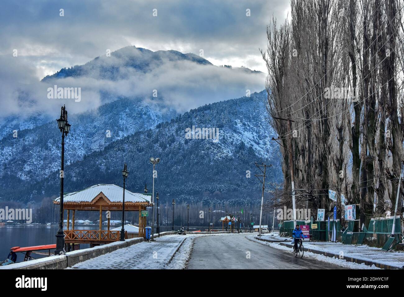 A cyclist rides along a road with snow covered mountains in the ...