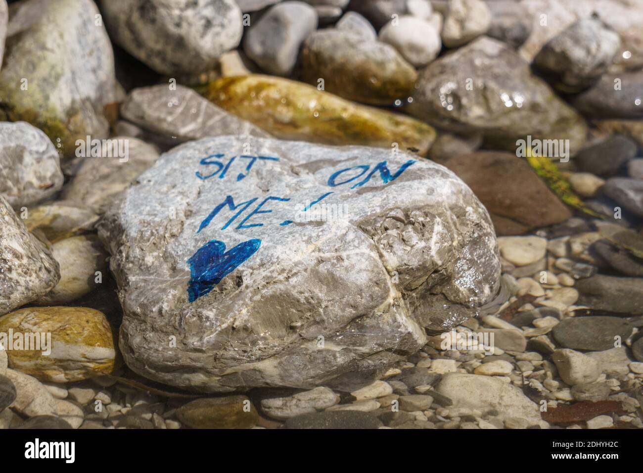Stone in river with letters telling sit on me Stock Photo - Alamy