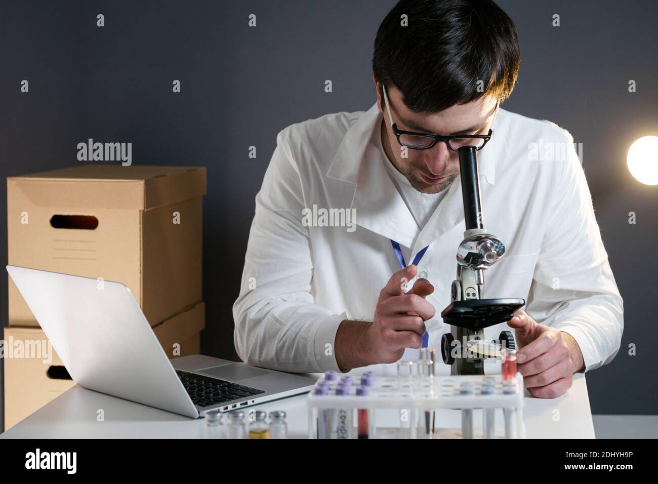 Scientist at workspace in laboratory with microscope, computer, and ...