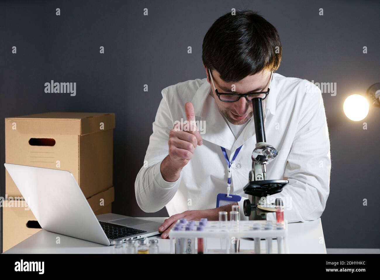 Scientist at workspace in laboratory with microscope, computer, and ...