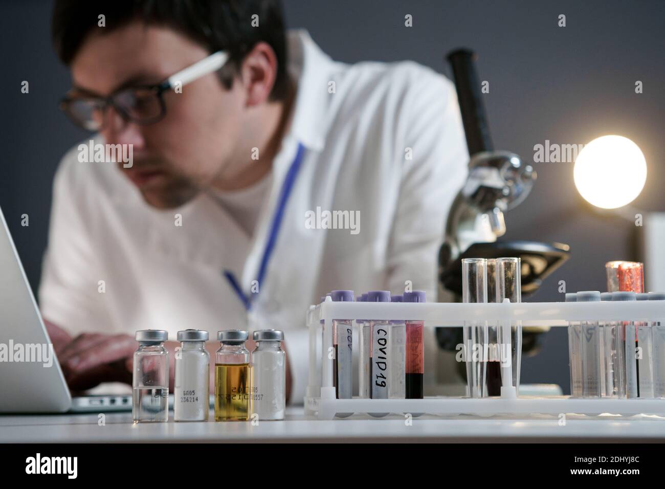 Scientist at workspace in laboratory with microscope, computer, and ...