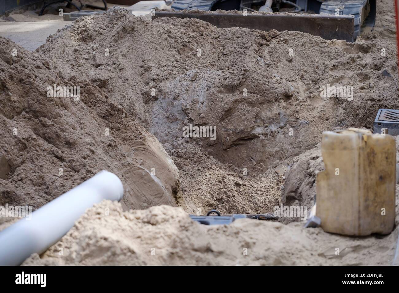 Construction of a road. A shovel pushes sand to a hole in the road, in ...