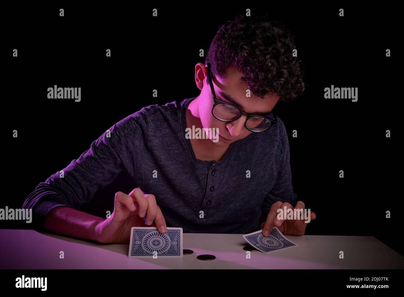 Young teenage Caucasian magician, doing a magic trick with cards on a ...
