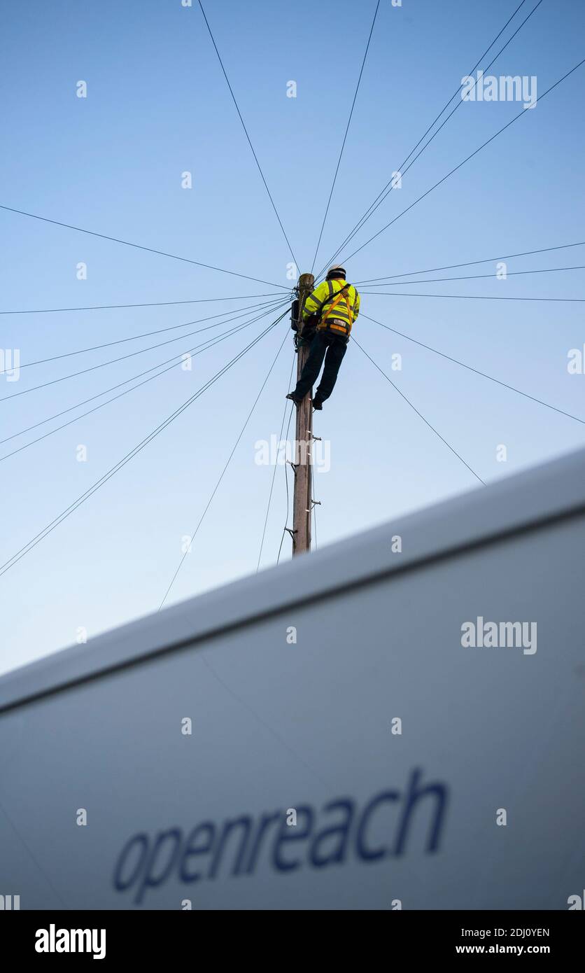 Telecommunications worker from Openreach climbs a wooden telegraph pole ...