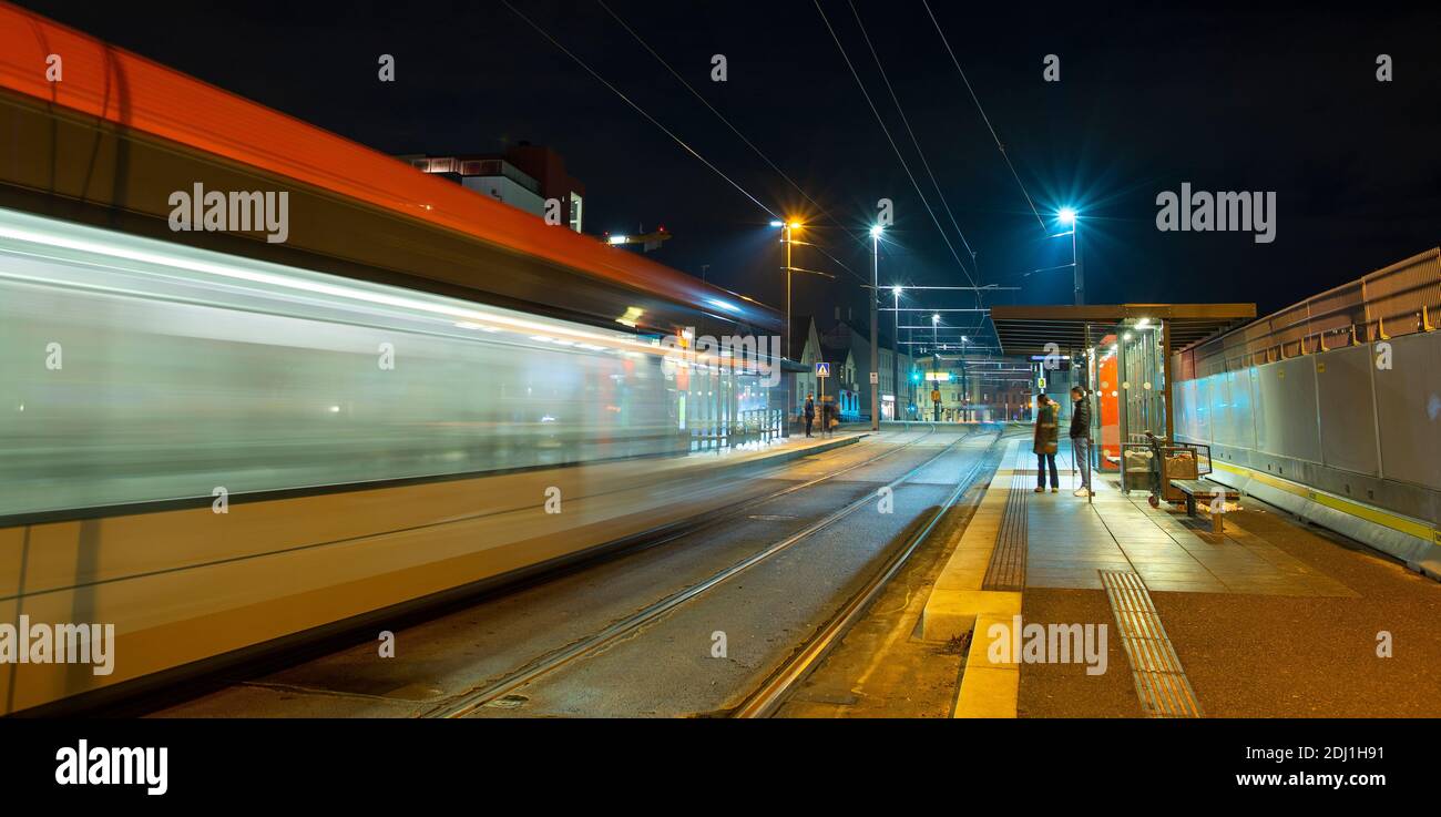 Tram passing a station in the night leaving a trail of light Stock ...
