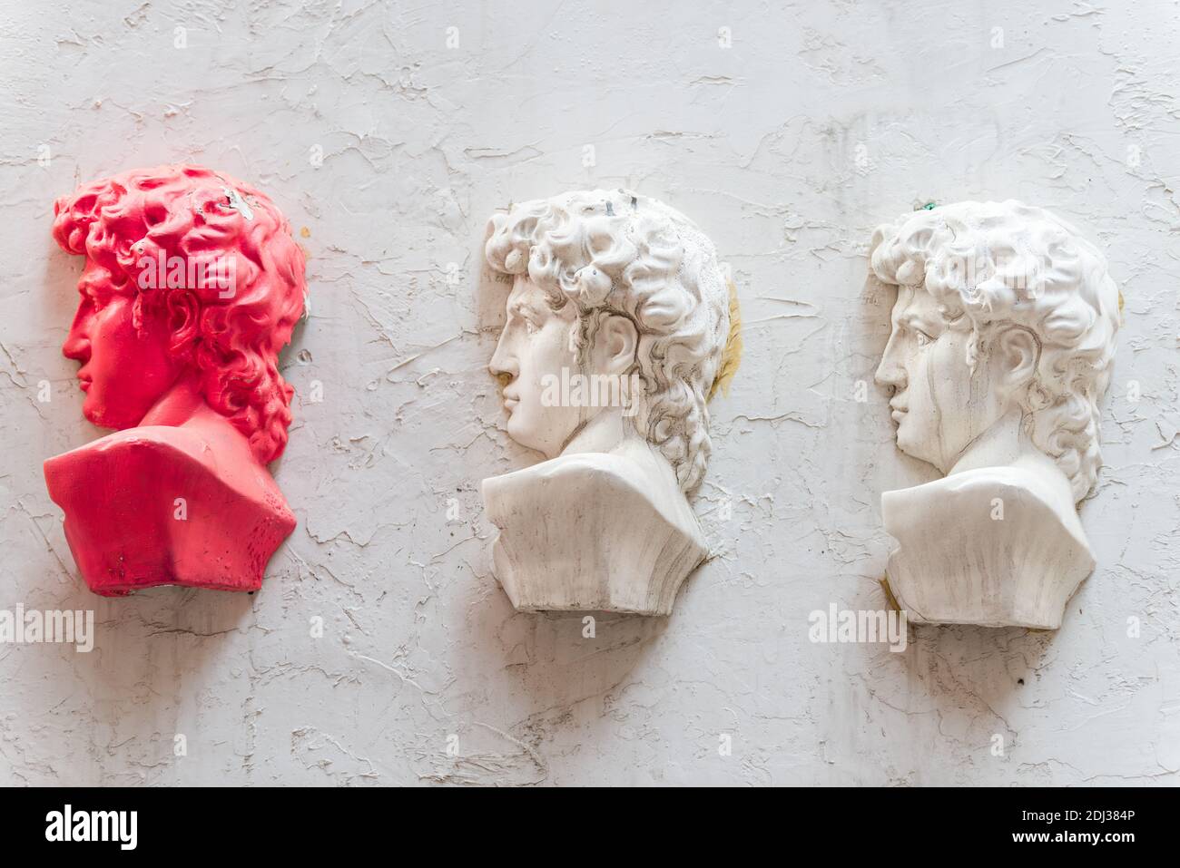 Three statues of david with colors of red and white on the wall in ...