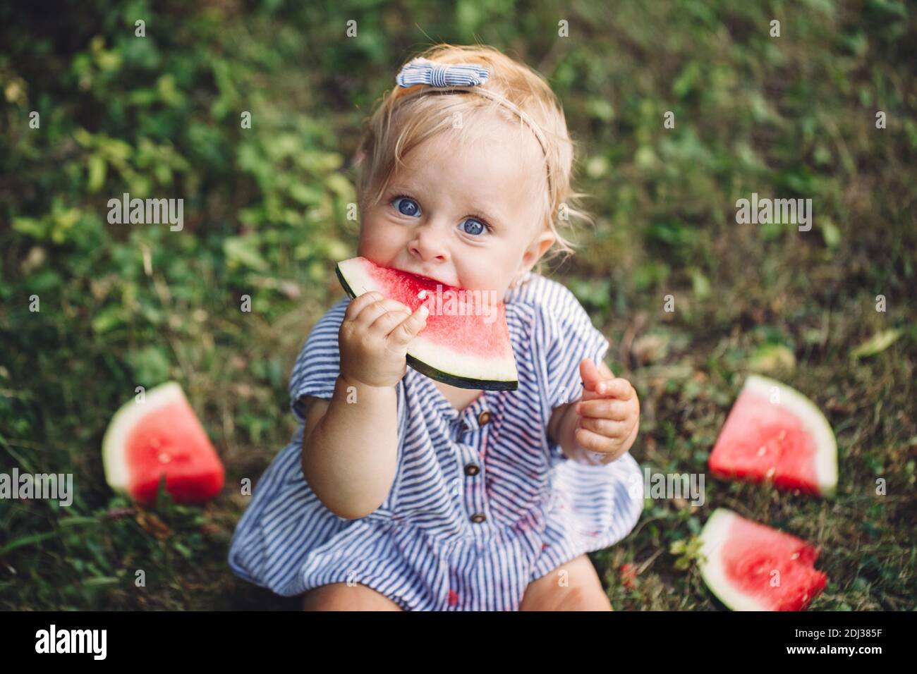 Cute Caucasian baby girl eating watermelon in park. Funny child kid ...