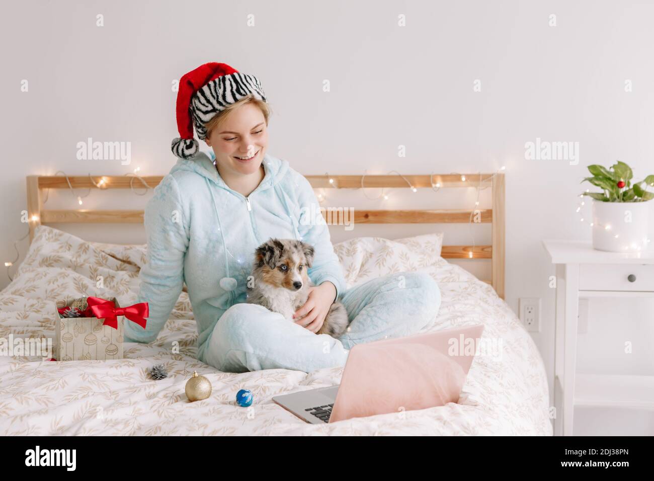 Smiling woman in Santa hat with cute puppy dog pet calling family ...