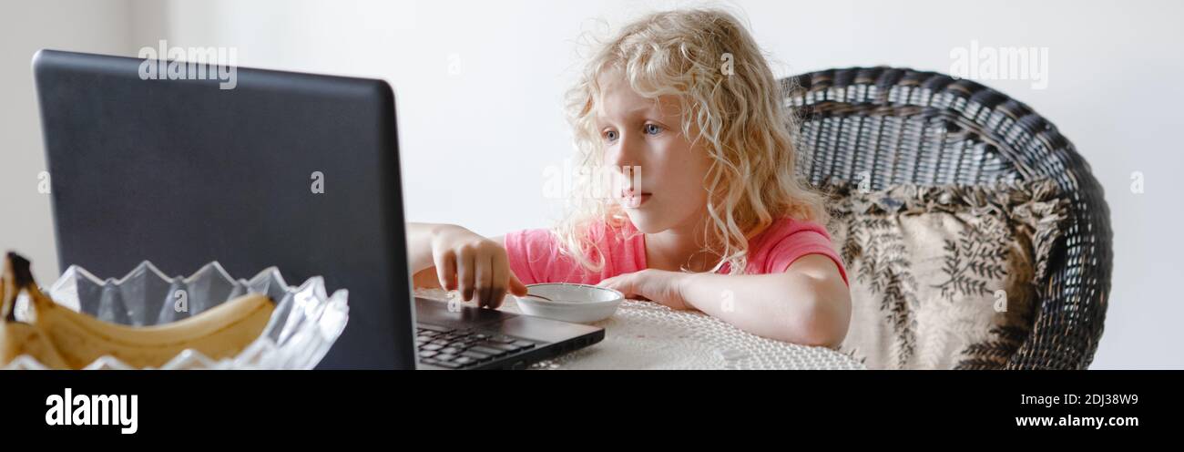 Girl eating food and watching cartoons on laptop. Child with digital ...