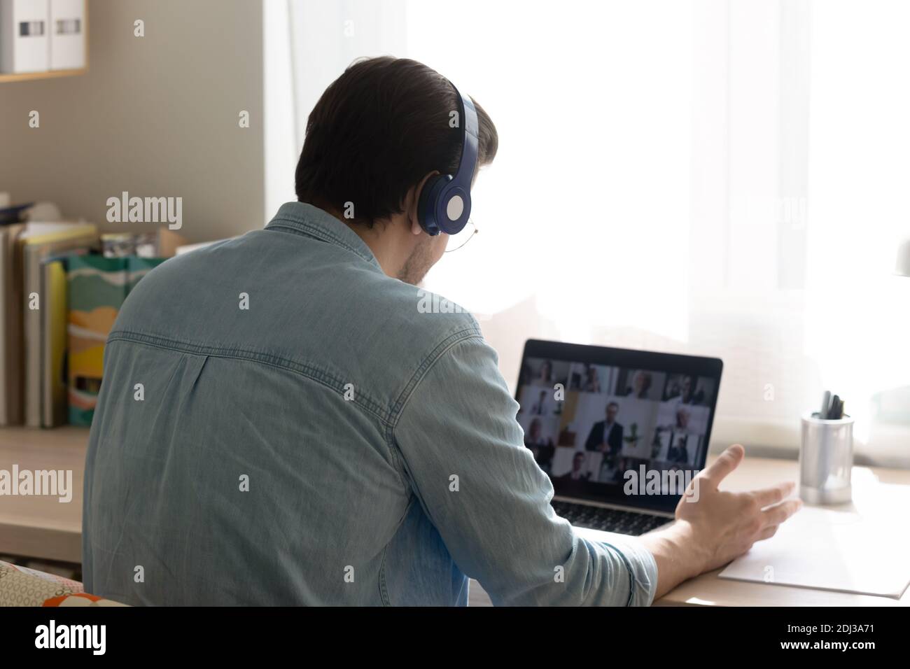 Rear view man wearing headphones engaged in online conference Stock ...