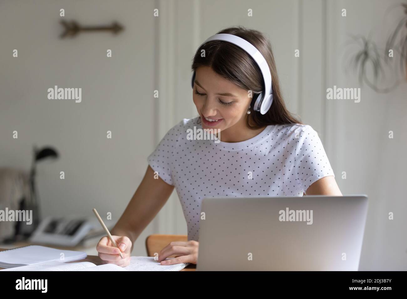 Close up wearing headphones writing notes, using laptop, studying ...