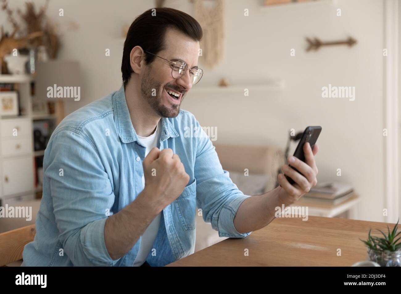 Overjoyed man holding smartphone, showing yes gesture, celebrate ...
