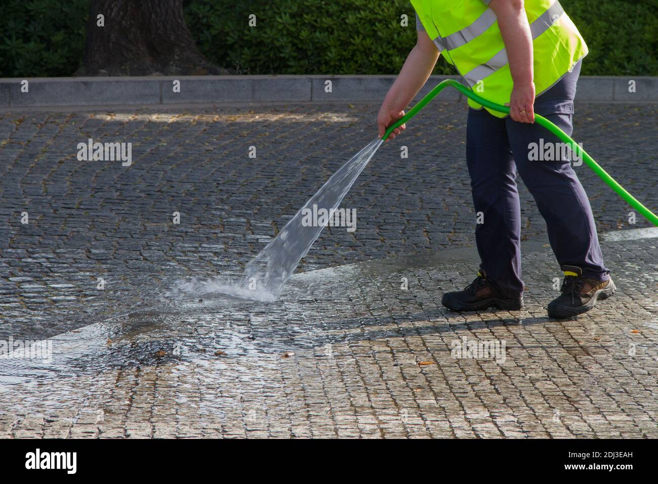 Worker washing sidewalk outside with spray pressure water Stock Photo ...