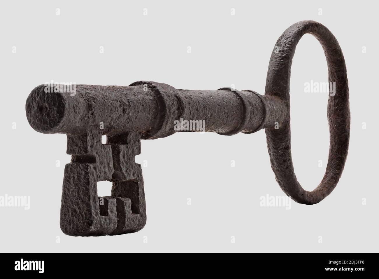 Antique iron key seen in oblique perspective against a plain light ...