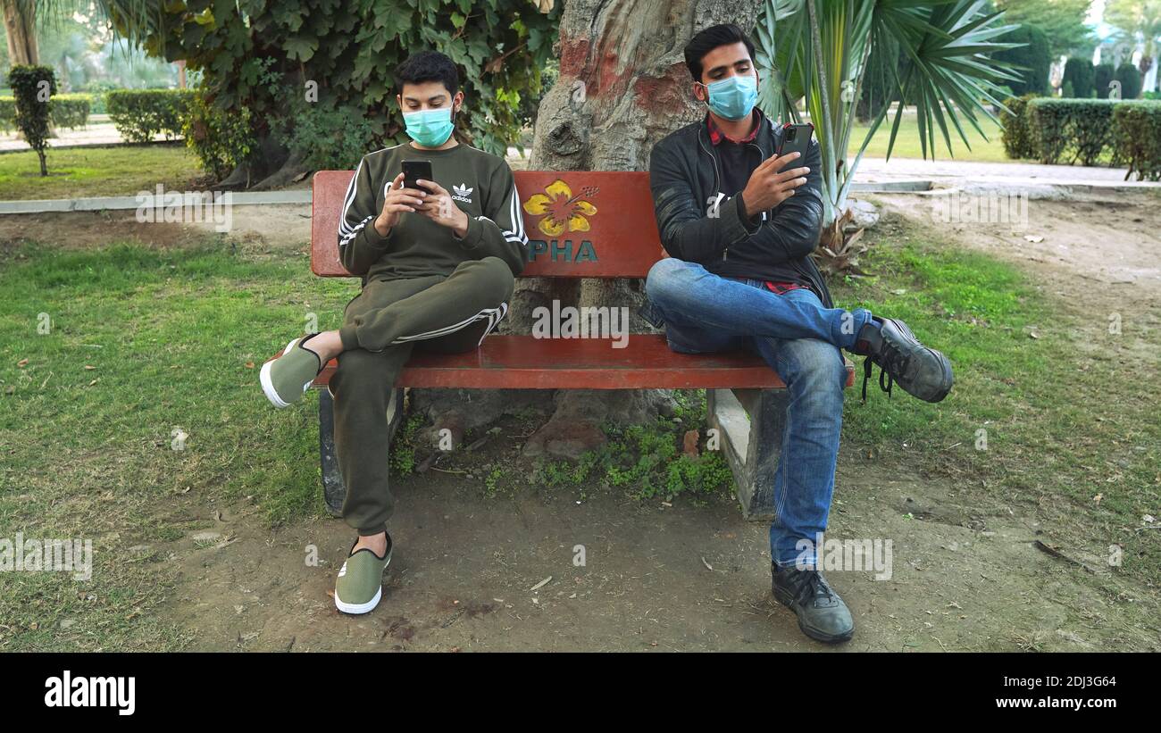 Friends sitting on bench Wearing Face Mask Stock Photo - Alamy