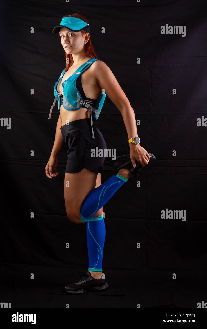 girl in blue jogging uniform runs in the studio on a black background ...
