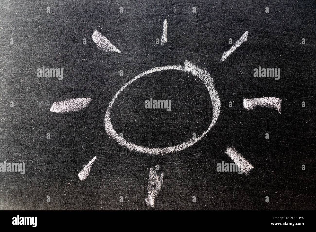 White color chalk hand drawing in sun with ray shape on blackboard ...