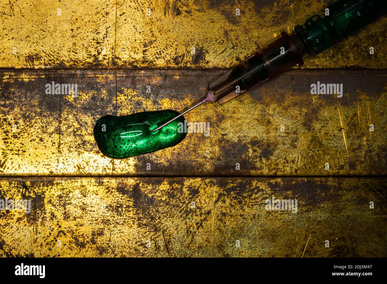 Close up of neon green fluid dripping and pooling from syringe on ...
