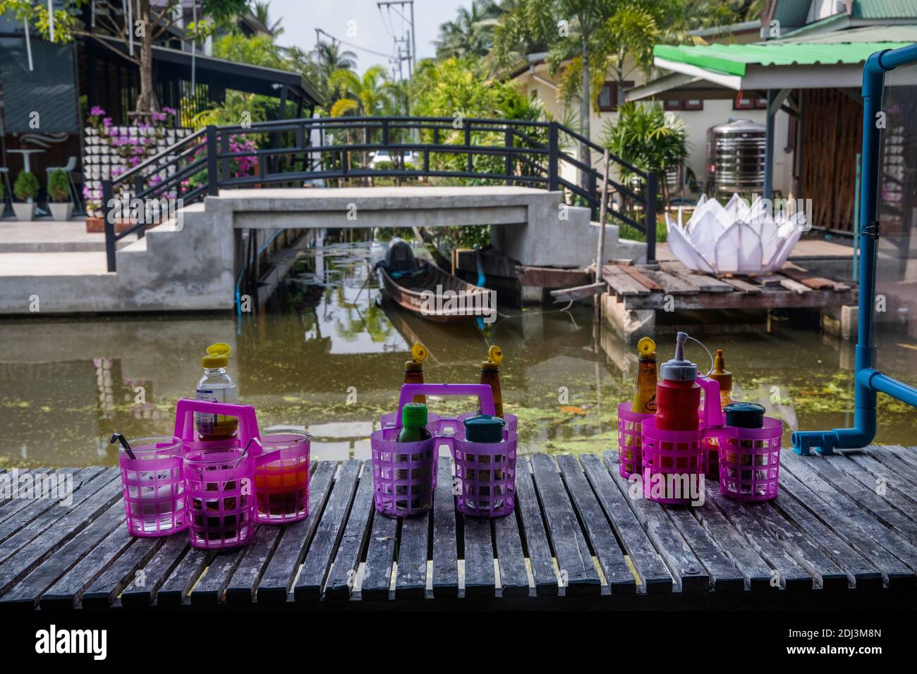 Condiments sit on a table at an eatery in the Amphawa Floating Market ...