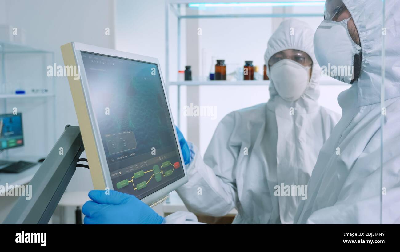 Chemists in protection suit discussing about changes in vaccine ...