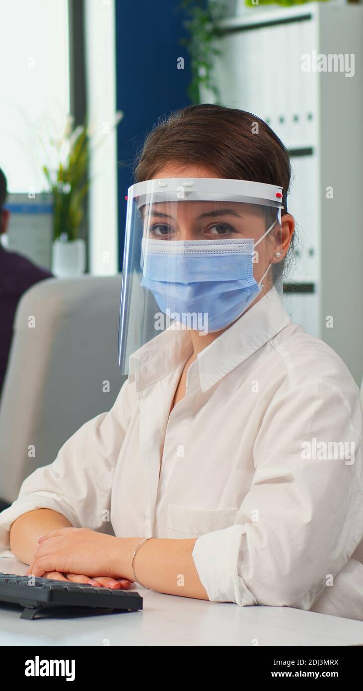 Manager woman with visor and protection mask looking at camera smiling ...