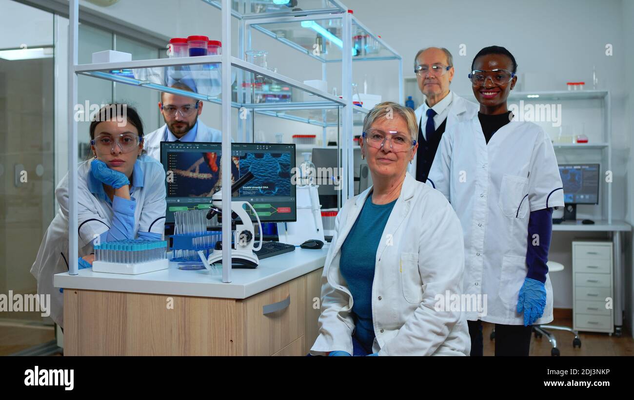 Team of multiethnic scientists sitting in laboratory looking at camera ...
