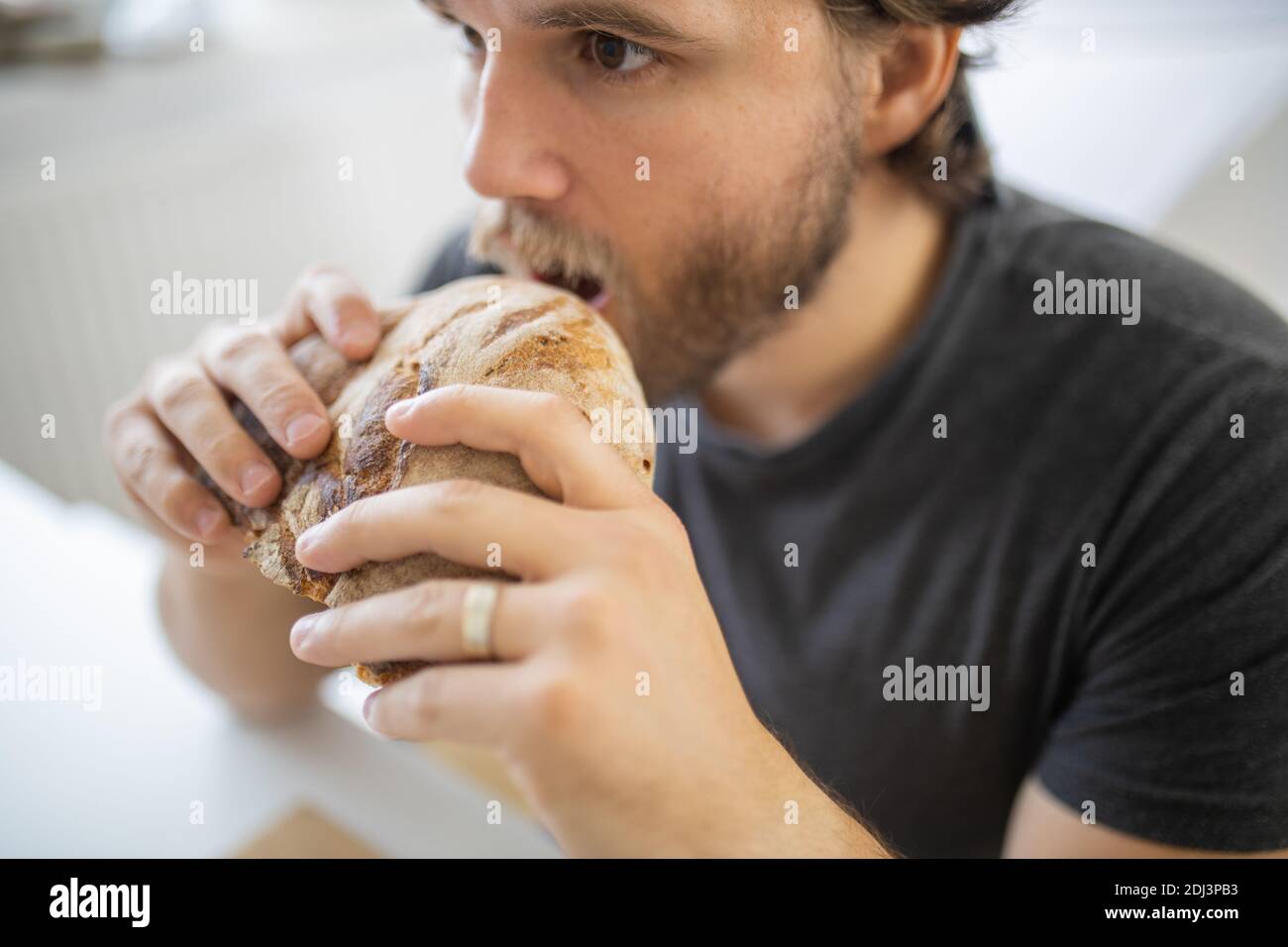 Surprised-looking man at a white table eating bread Stock Photo - Alamy