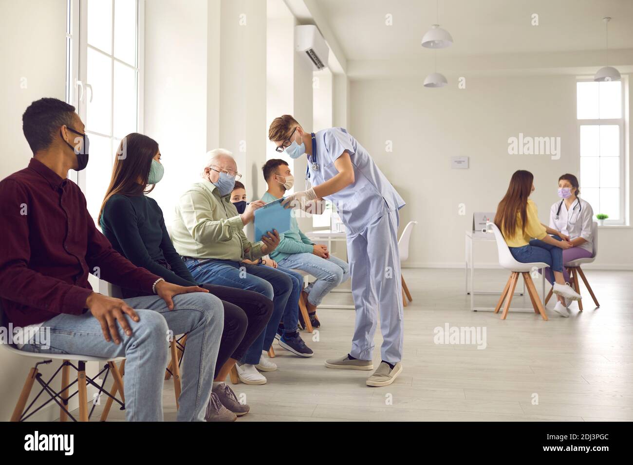 Diverse people waiting in line at the hospital and signing papers that ...