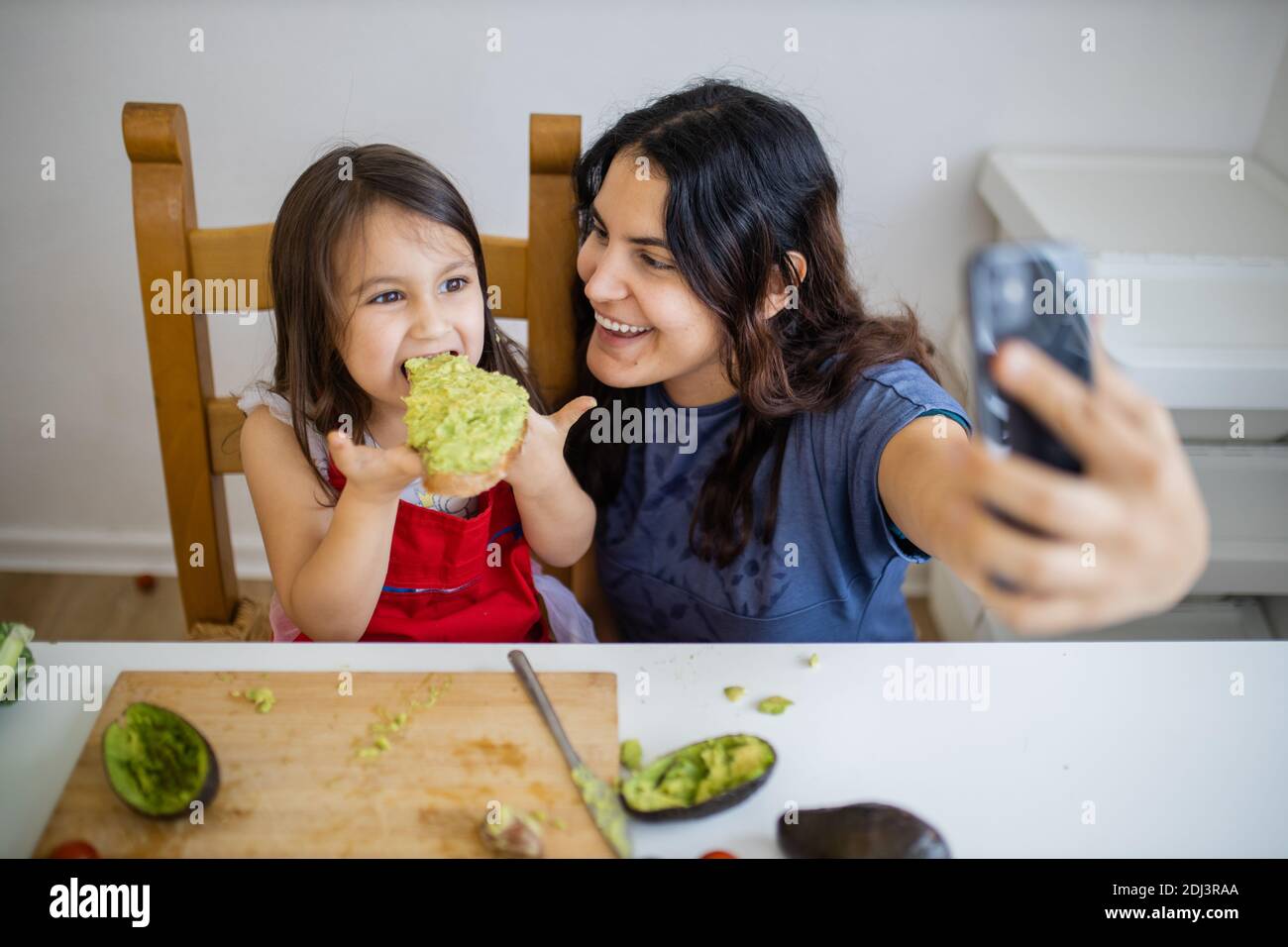 Mother and daughter taking a selfie while eating an avocado toast Stock ...