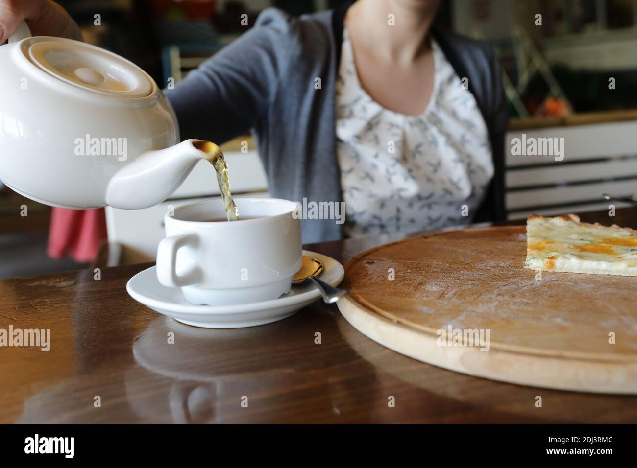 Person pouring tea into teacap in cafe Stock Photo - Alamy