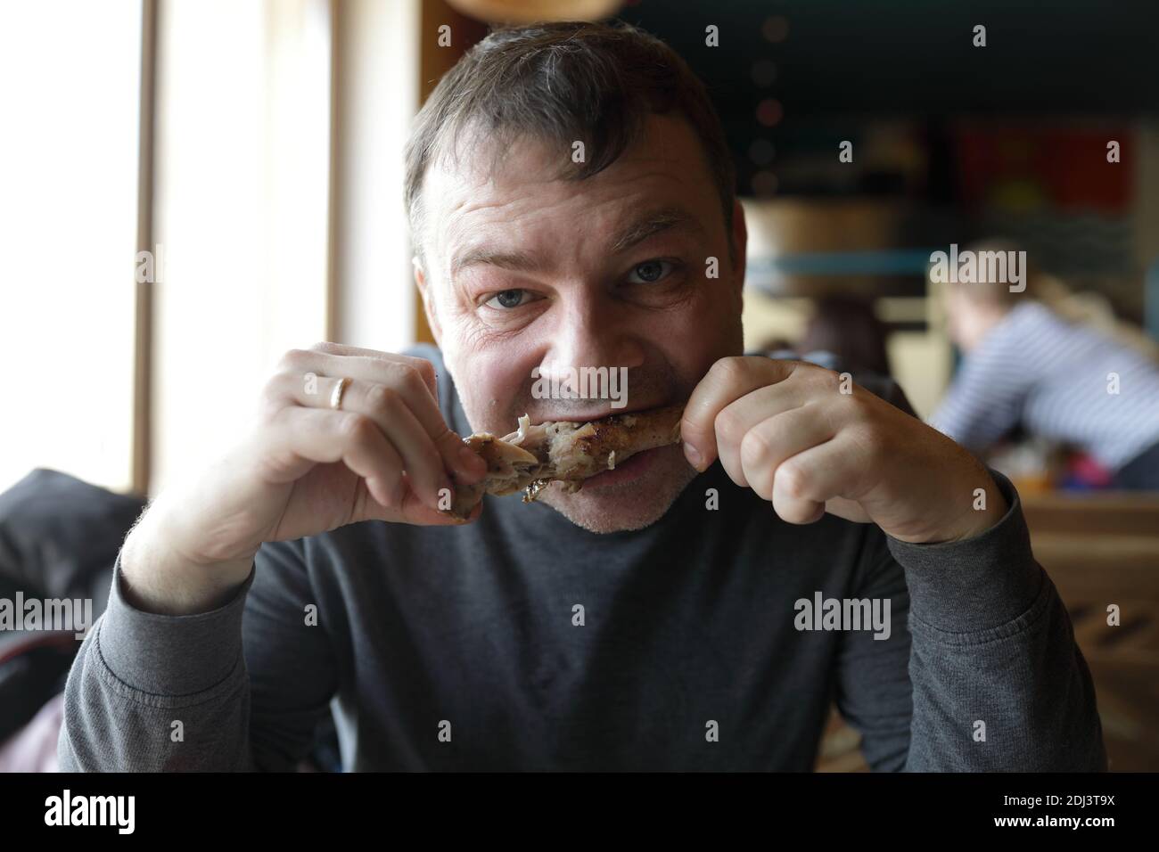 Man eating chicken leg in a restaurant Stock Photo - Alamy