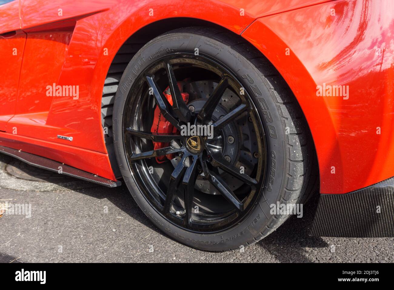 Close up detail of the rear gloss black wheel of a Rosso Mars red ...