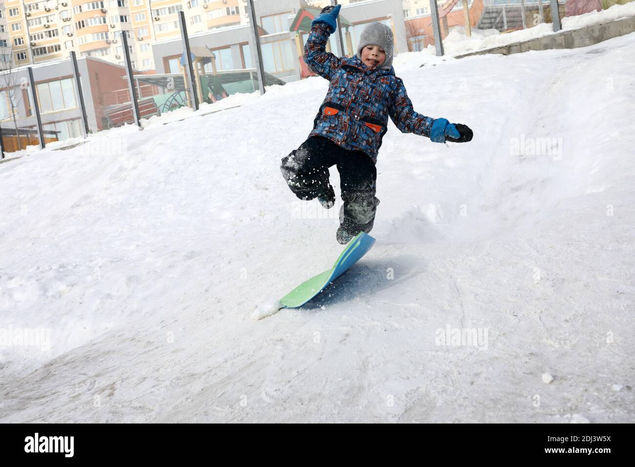 Boy sliding down snow hill in winter Stock Photo - Alamy