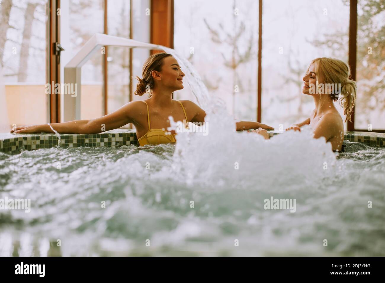 Pretty young women relaxing in the whirlpool bathtub at the poolside ...