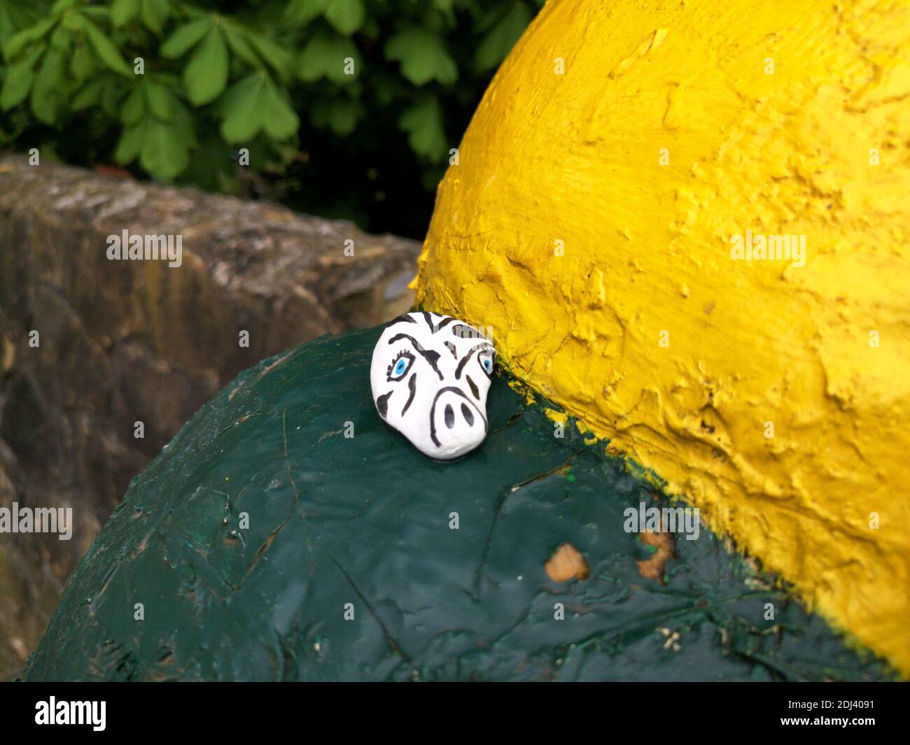 A high angle closeup of a small object shaped like an old mask in a gar ...