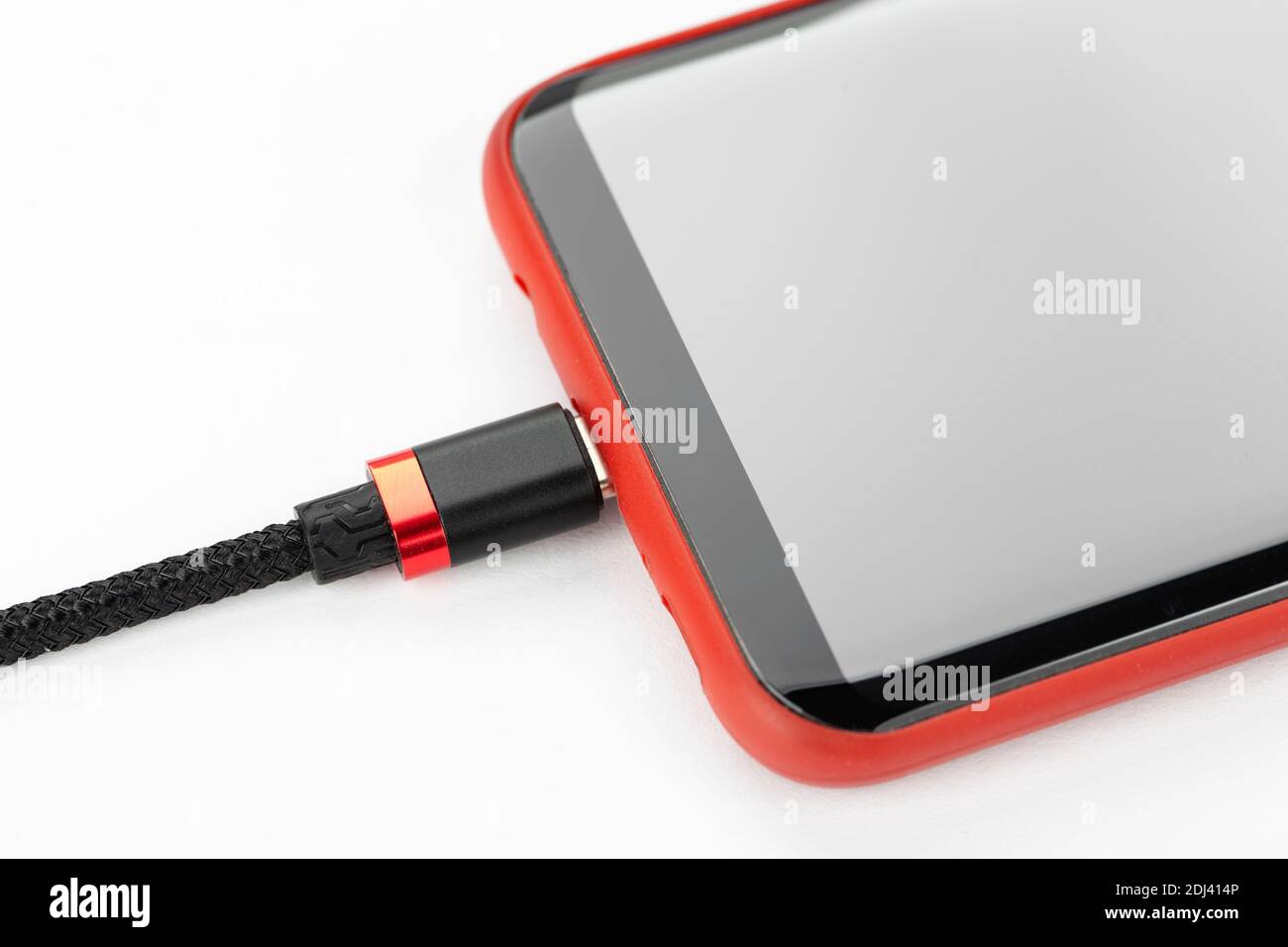 Mobile phone in a red case with a connected cable for charging power on ...