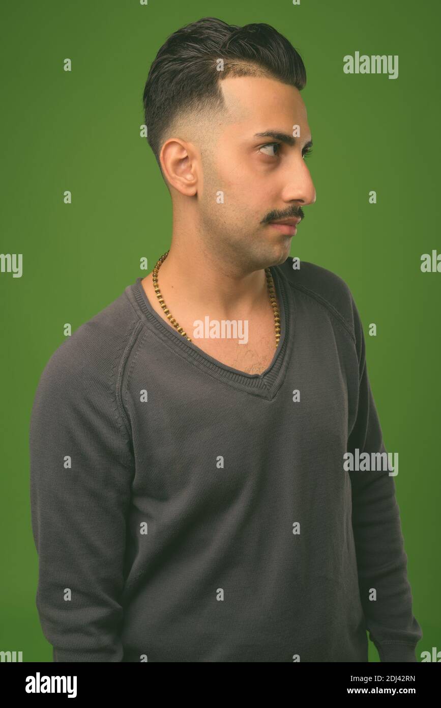 Young handsome Iranian man with mustache against green background Stock ...