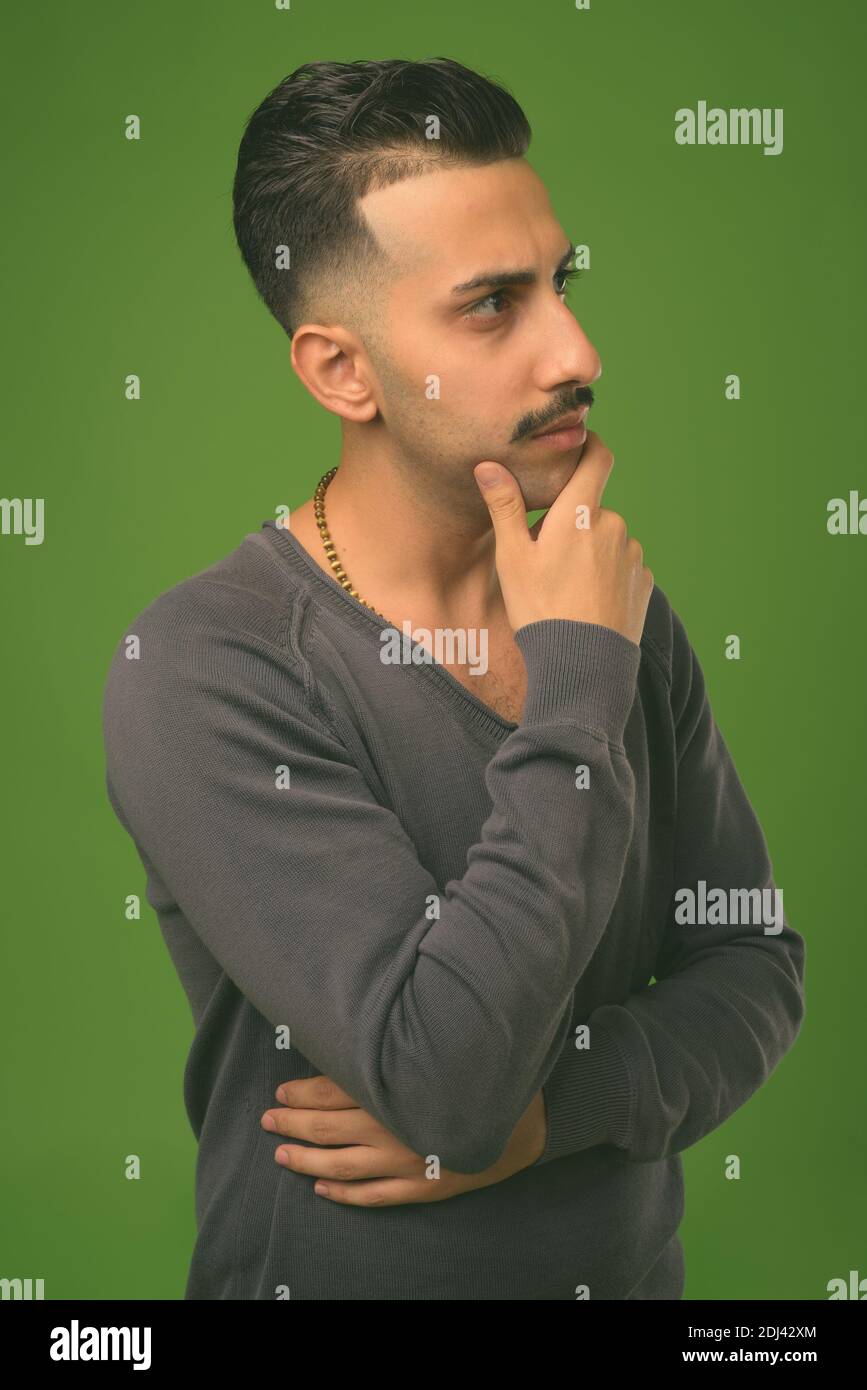 Young handsome Iranian man with mustache against green background Stock ...