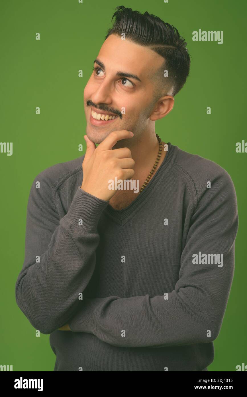 Young handsome Iranian man with mustache against green background Stock ...